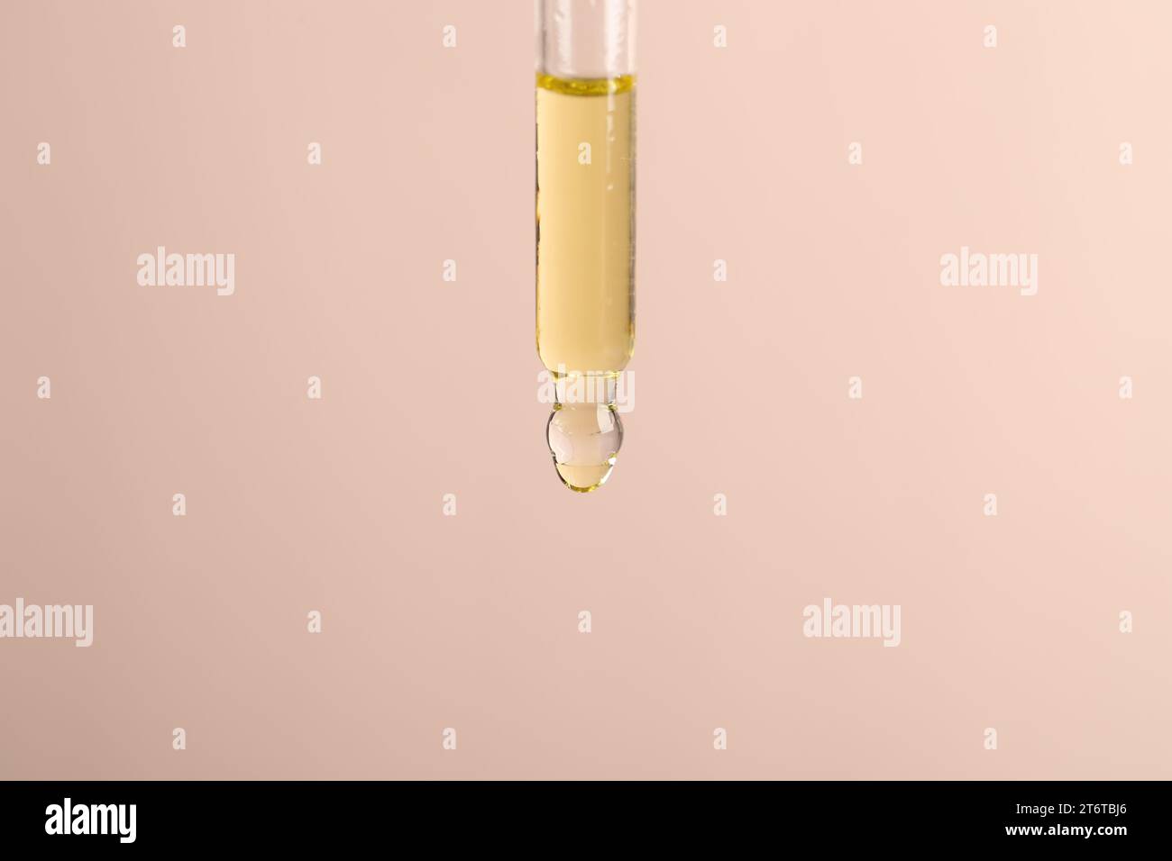 Dripping cosmetic serum from pipette on beige background Stock Photo ...