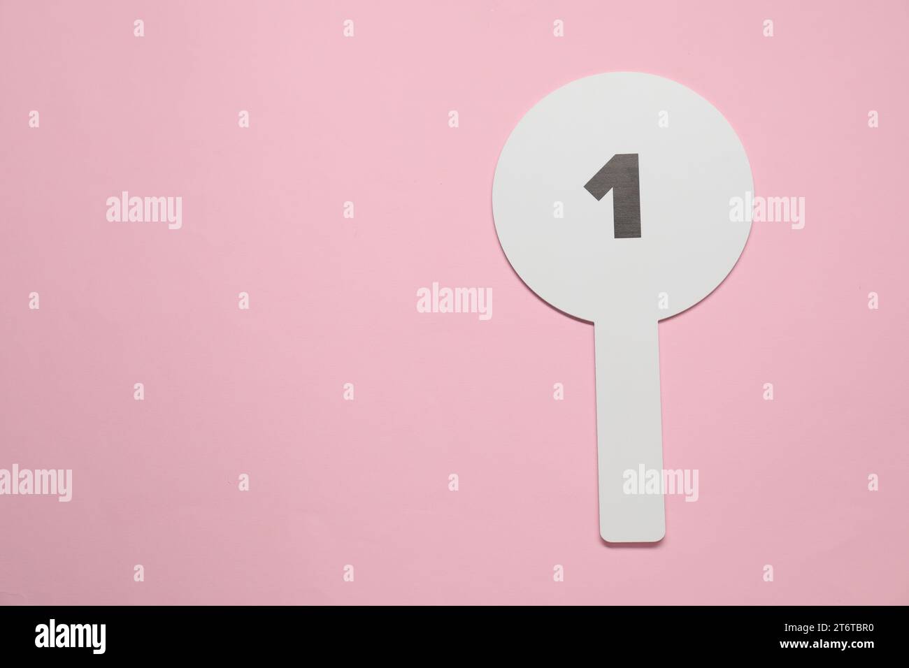 Auction paddle with number 1 on pink background, top view. Space for ...