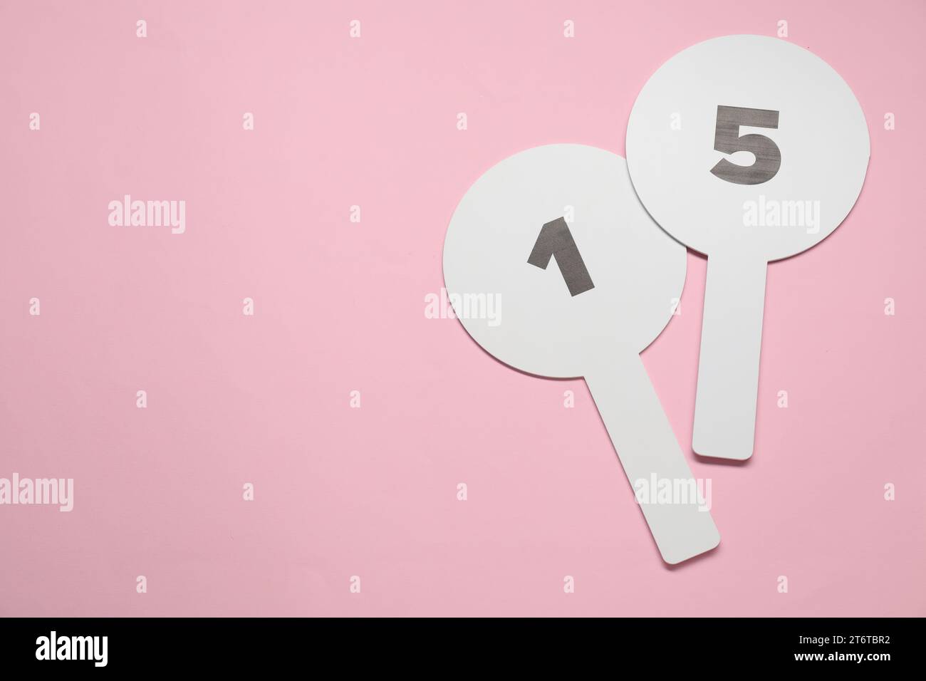 Auction paddles with numbers on pink background, top view. Space for ...