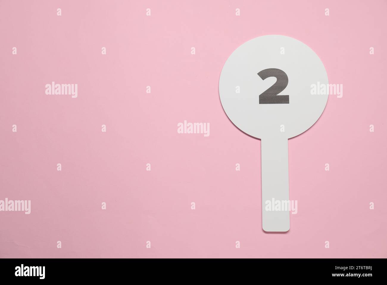 Auction paddle with number 2 on pink background, top view. Space for ...
