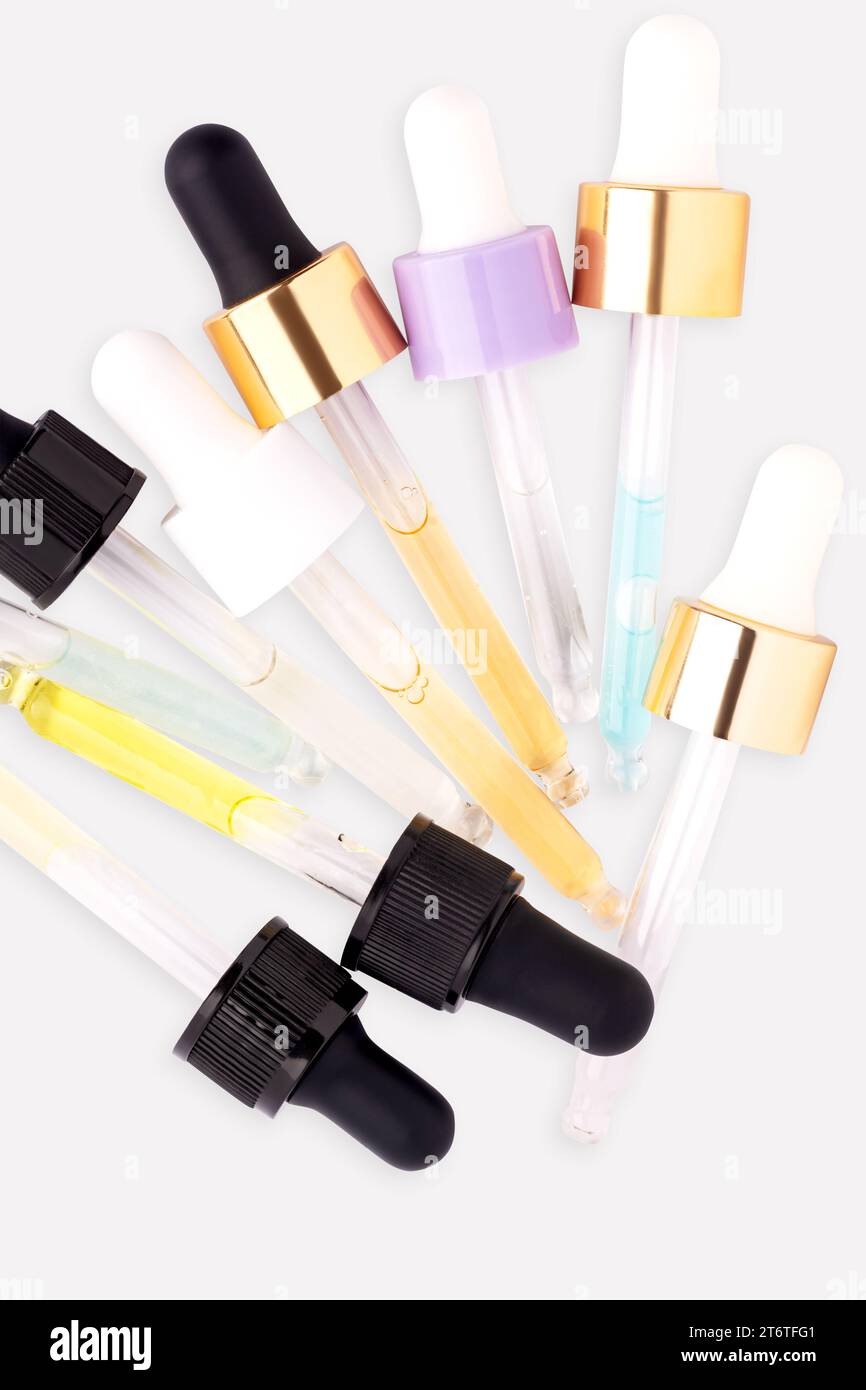 many pipette droppers with pouring serum and droplets on a white ...