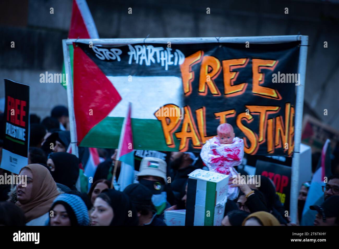 A protestor holds a large banner with an effigy of a child during the ...