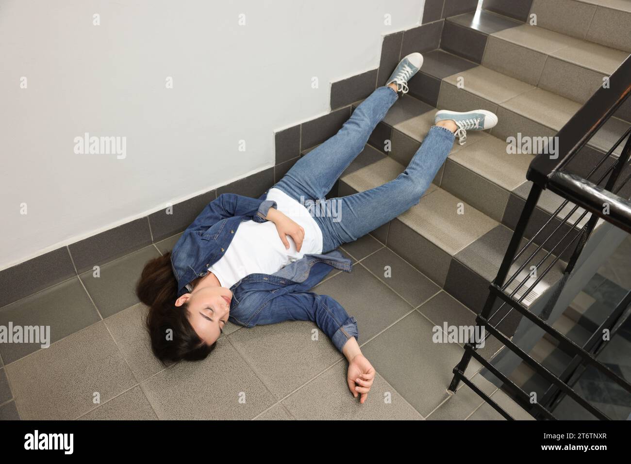 Unconscious woman lying on floor after falling down stairs indoors ...