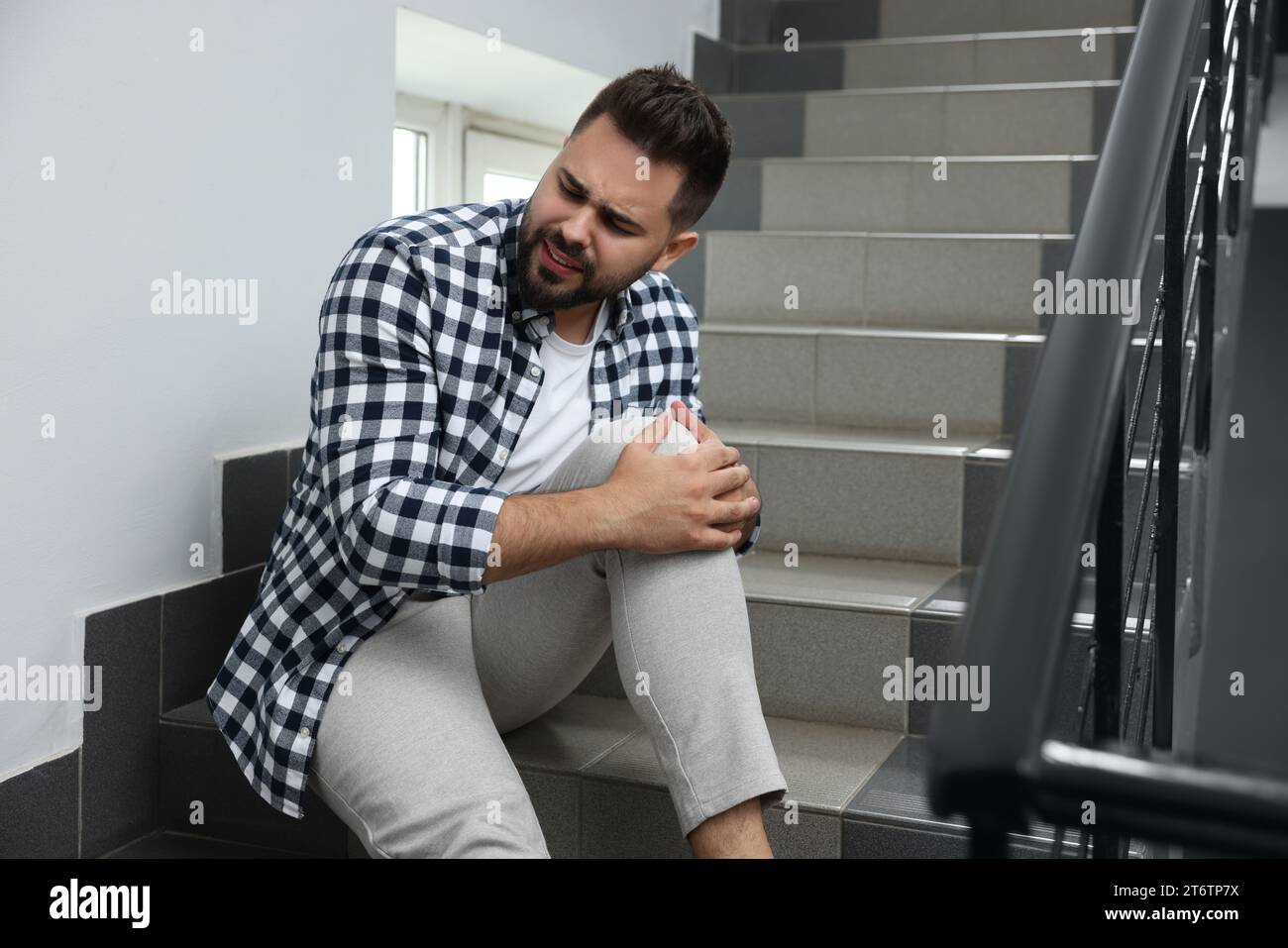 Man fallen down stairs suffering from pain in knee indoors Stock Photo ...