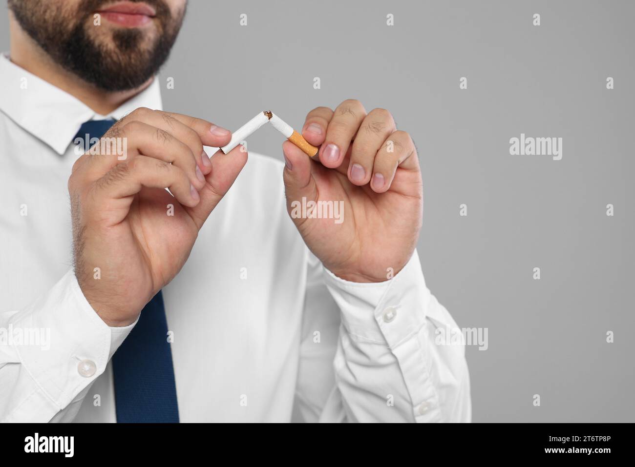 Stop smoking concept. Man breaking cigarette on light grey background ...