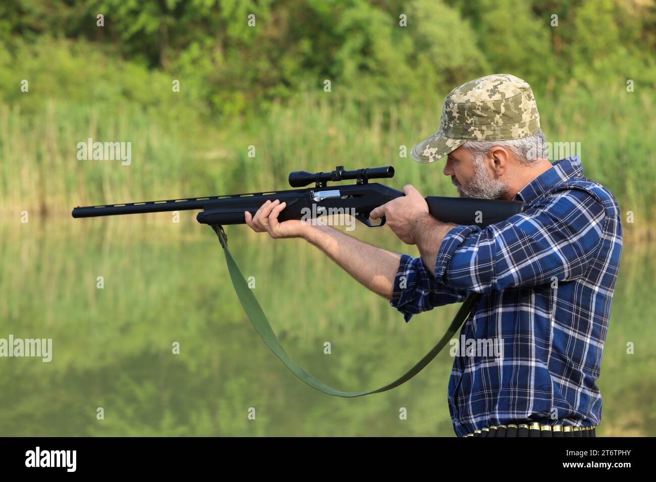Man aiming with hunting rifle near lake outdoors Stock Photo - Alamy