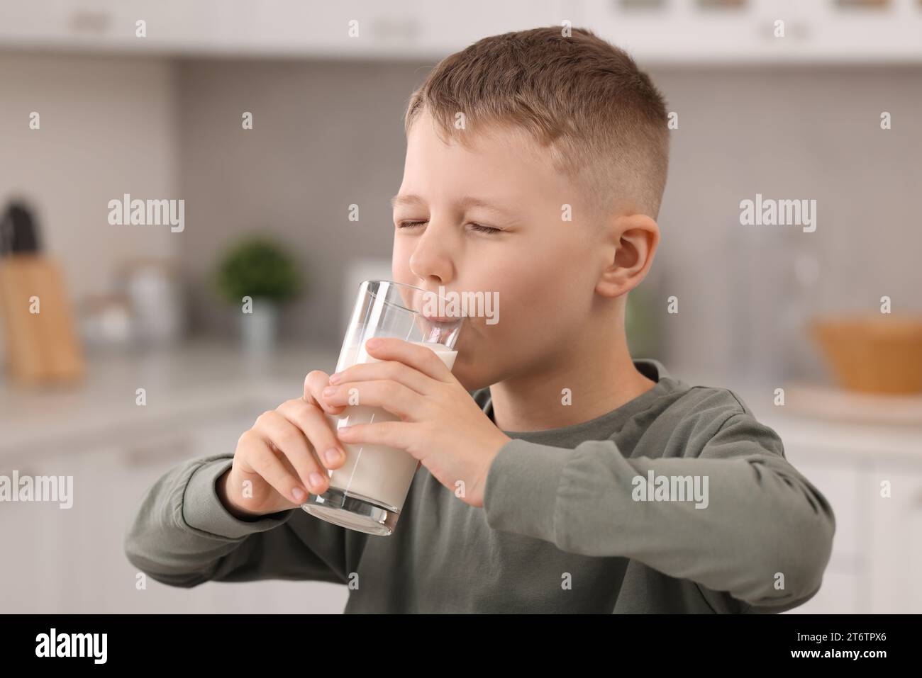 Cute boy drinking fresh milk from glass indoors Stock Photo - Alamy