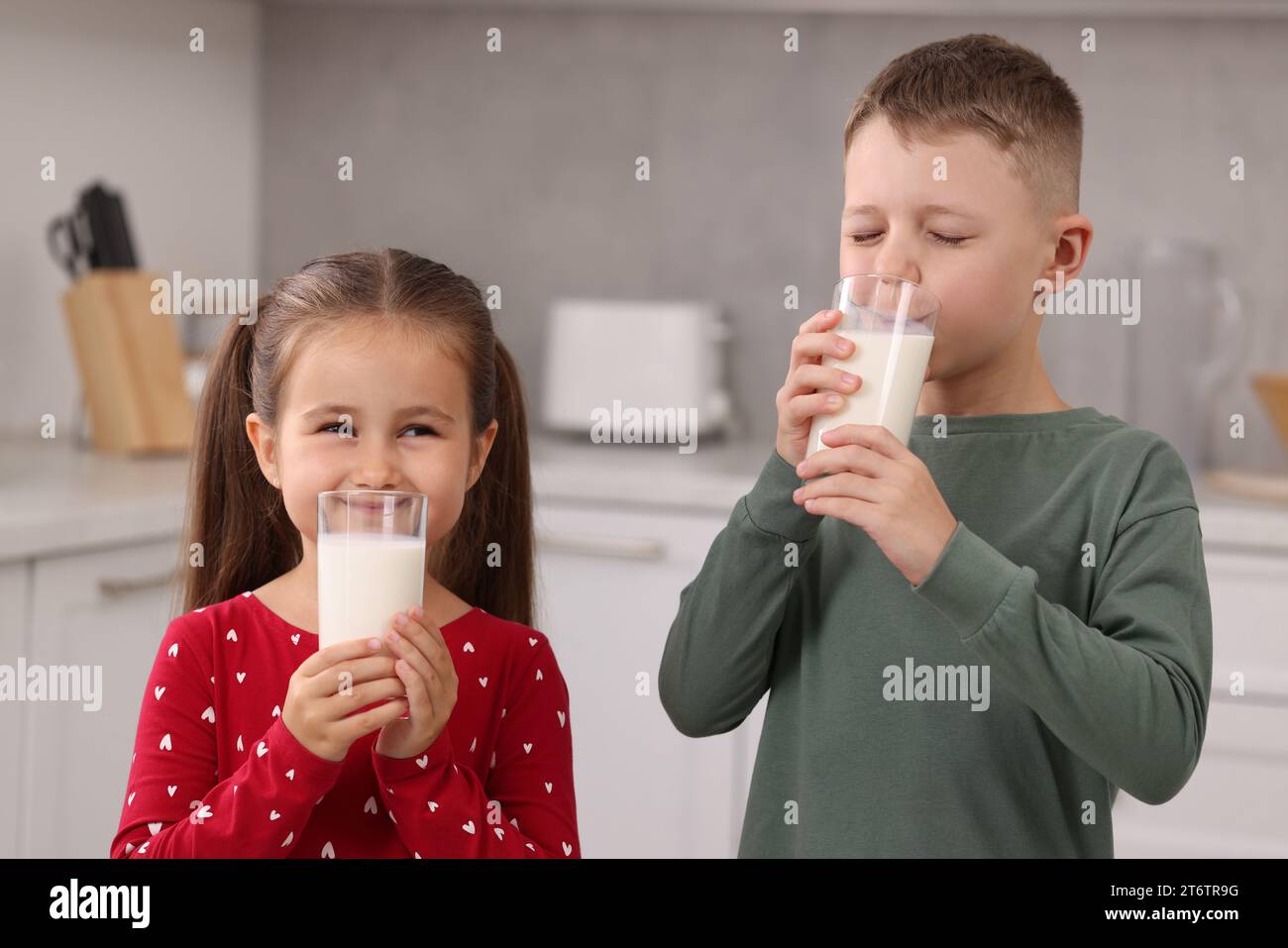 Cute children drinking fresh milk from glasses in kitchen Stock Photo ...
