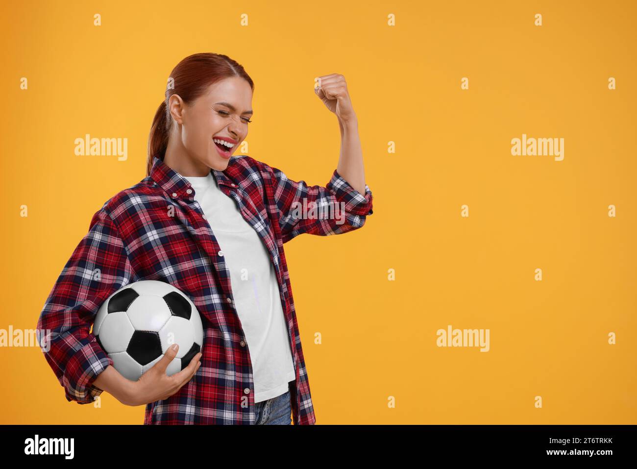 Happy fan holding football ball and celebrating on yellow background ...