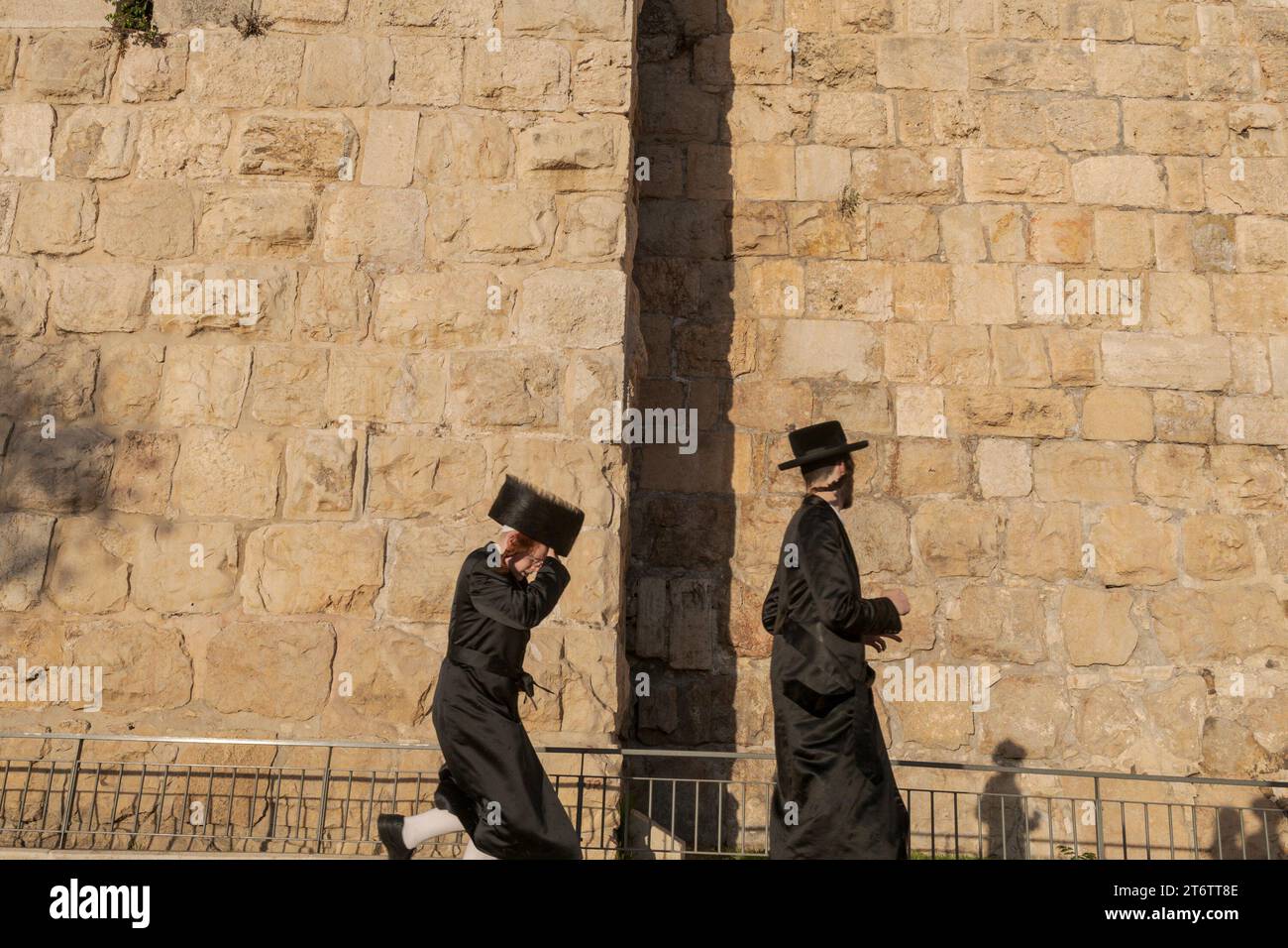 Two men from the Orthodox Jewish community walking around the walls of ...
