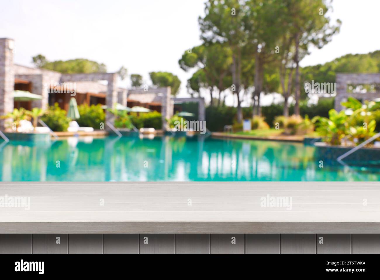 Empty white wooden desk near outdoor swimming pool at resort, space for ...