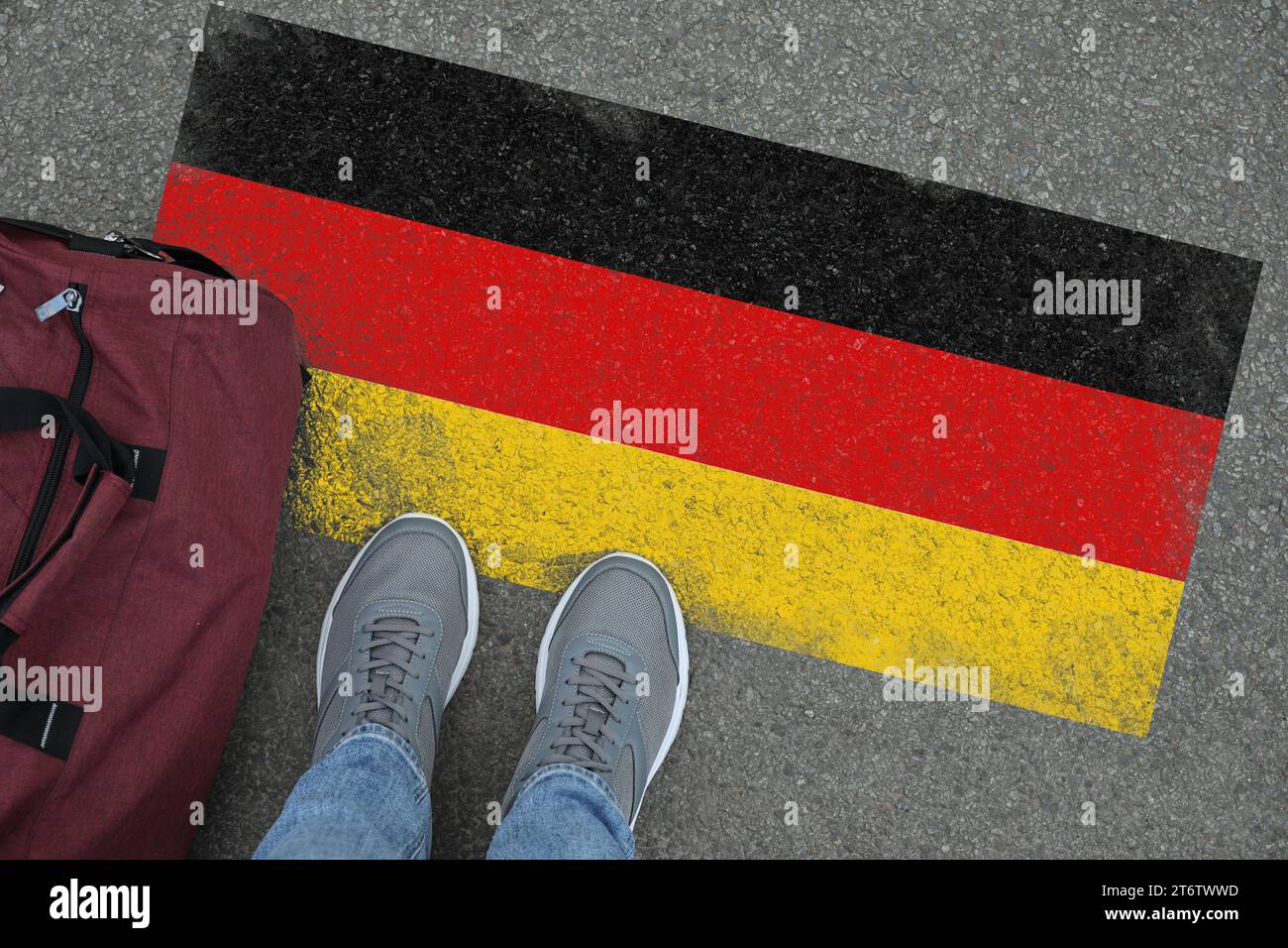 Immigration. Man with bag standing on asphalt near flag of Germany, top ...