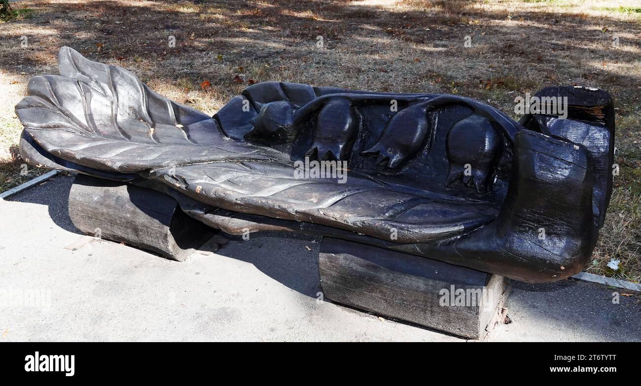 A bench with artistic wood cutting is installed in a summer park in ...