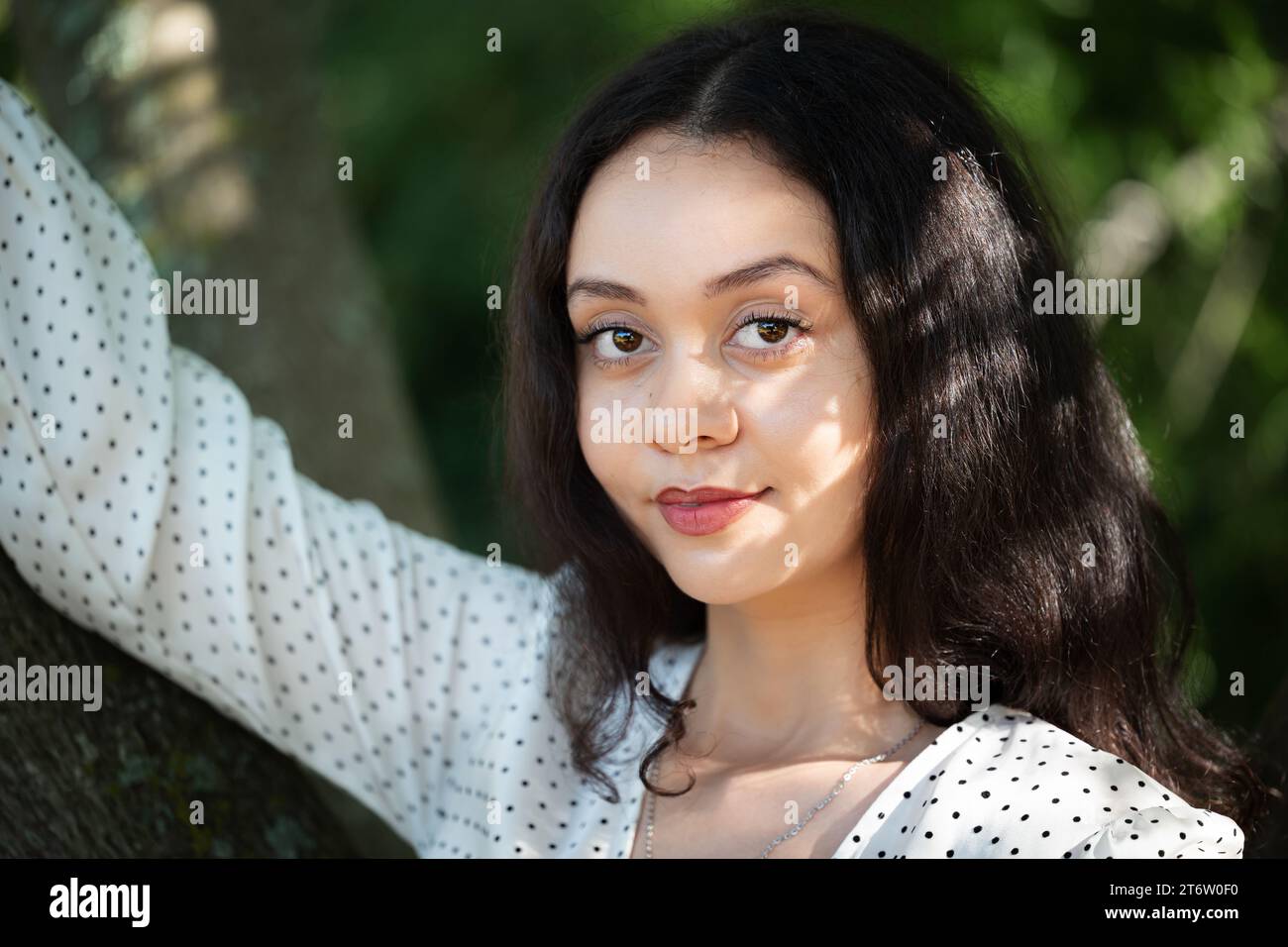 A female adult stands in a peaceful, woody environment with her back ...