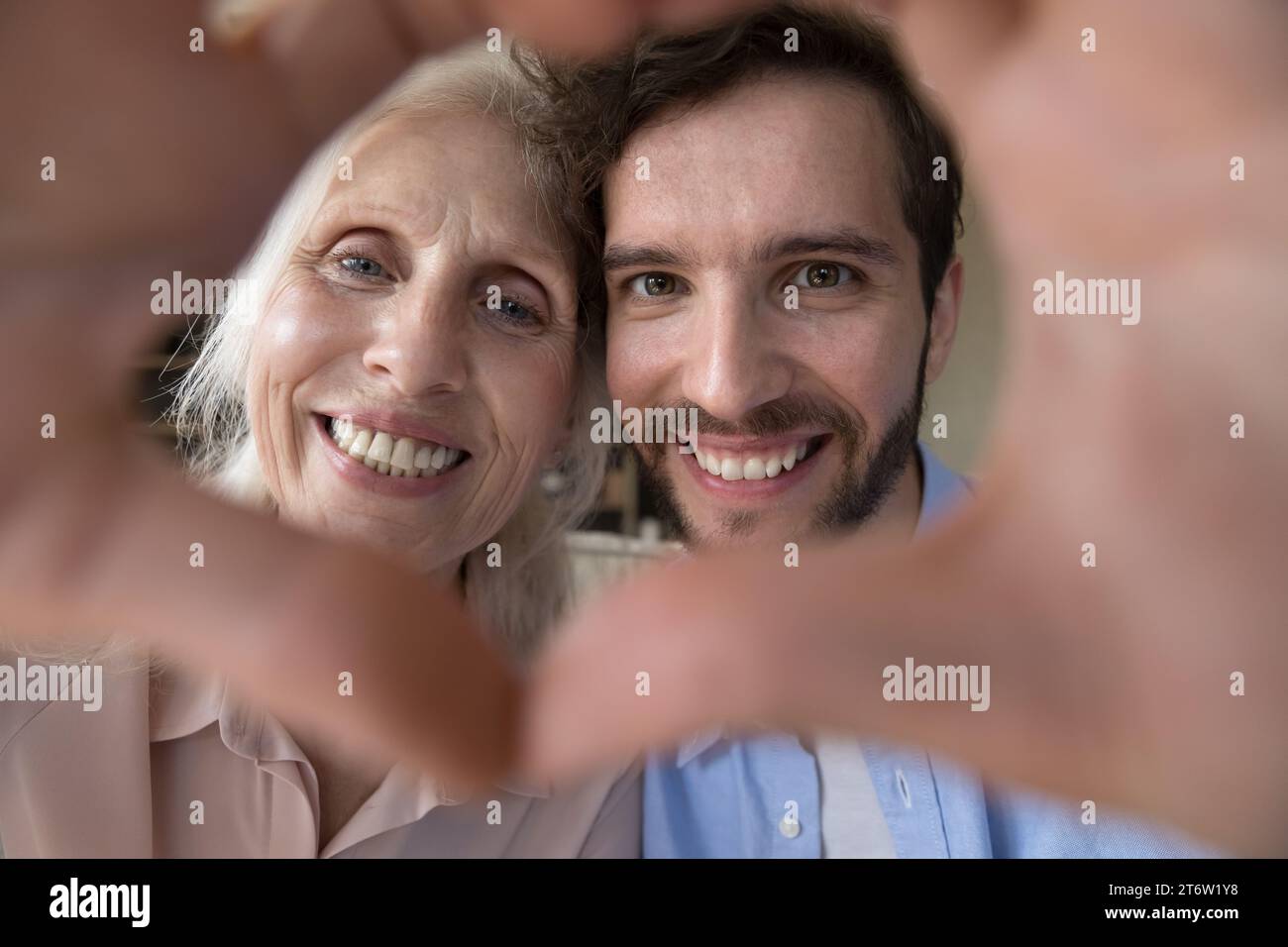 Adult son and old mother show love sign Stock Photo - Alamy