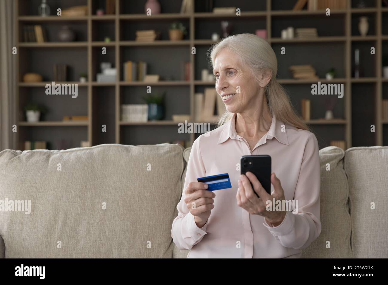 Mature woman buying goods using card, cellphone and mobile application ...