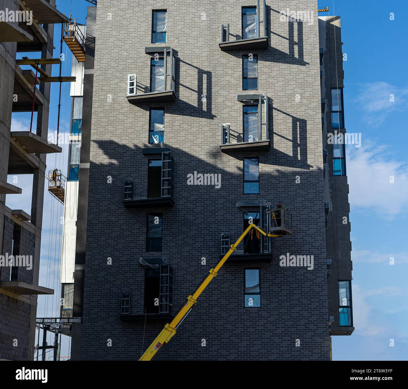 Finishing building works outdoors. Construction crane and balcony works ...