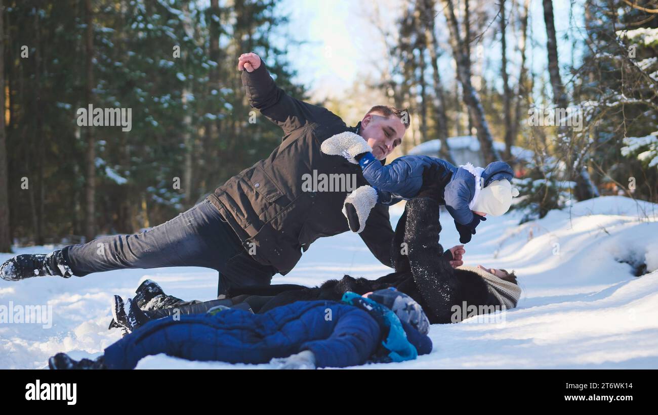 A mother and her child playing in the winter woods, falling in the snow ...