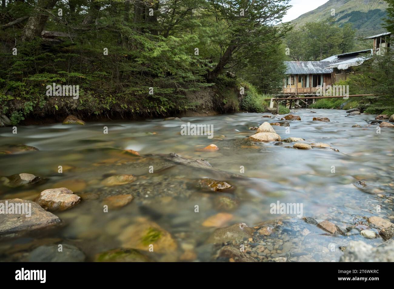Crystal clear stream with bedrock and an old cabin in the background ...