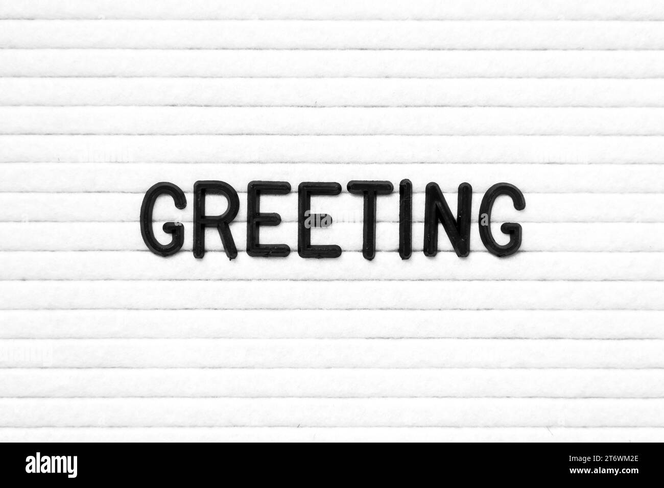Black color letter in word greeting on white felt board background ...