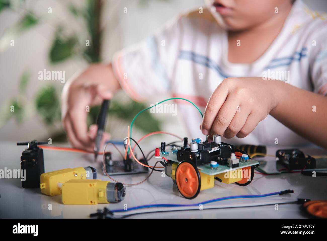 Asian kid boy plugging energy and signal cable to sensor chip with Arduino robot car Stock Photo ...