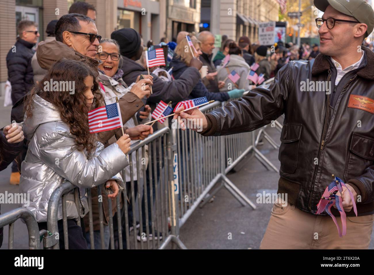 NEW YORK, NEW YORK - NOVEMBER 11: A participant hands out flag to ...