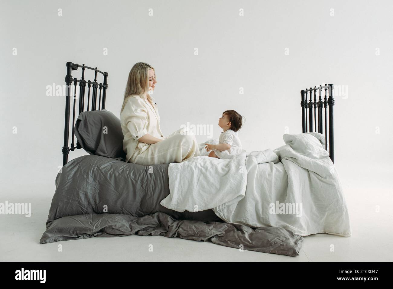 Happy mother plays with her child while sitting in bed, in the morning ...