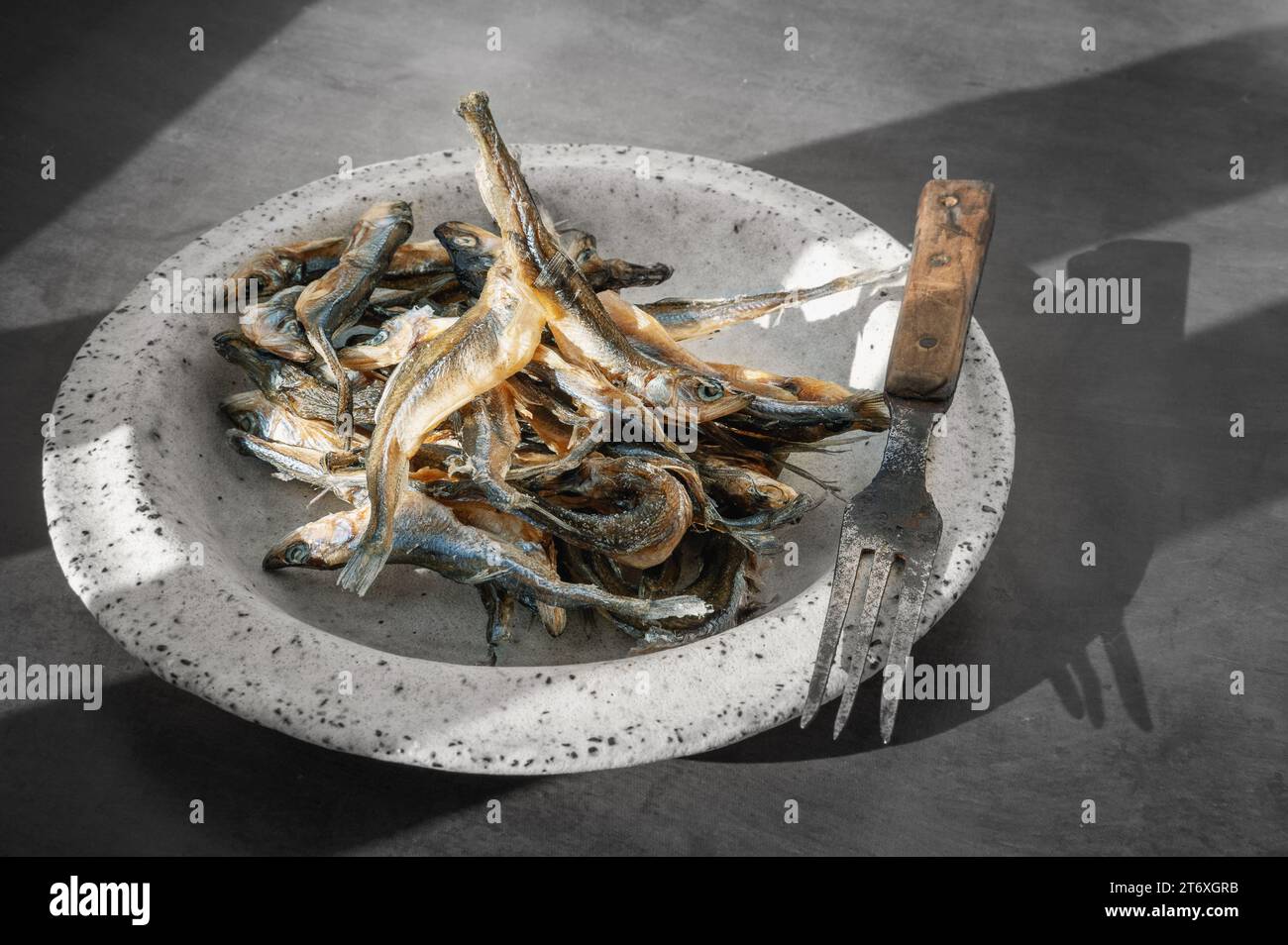 Dried salted smelt. Baltic dried smelt on a handmade round clay plate ...