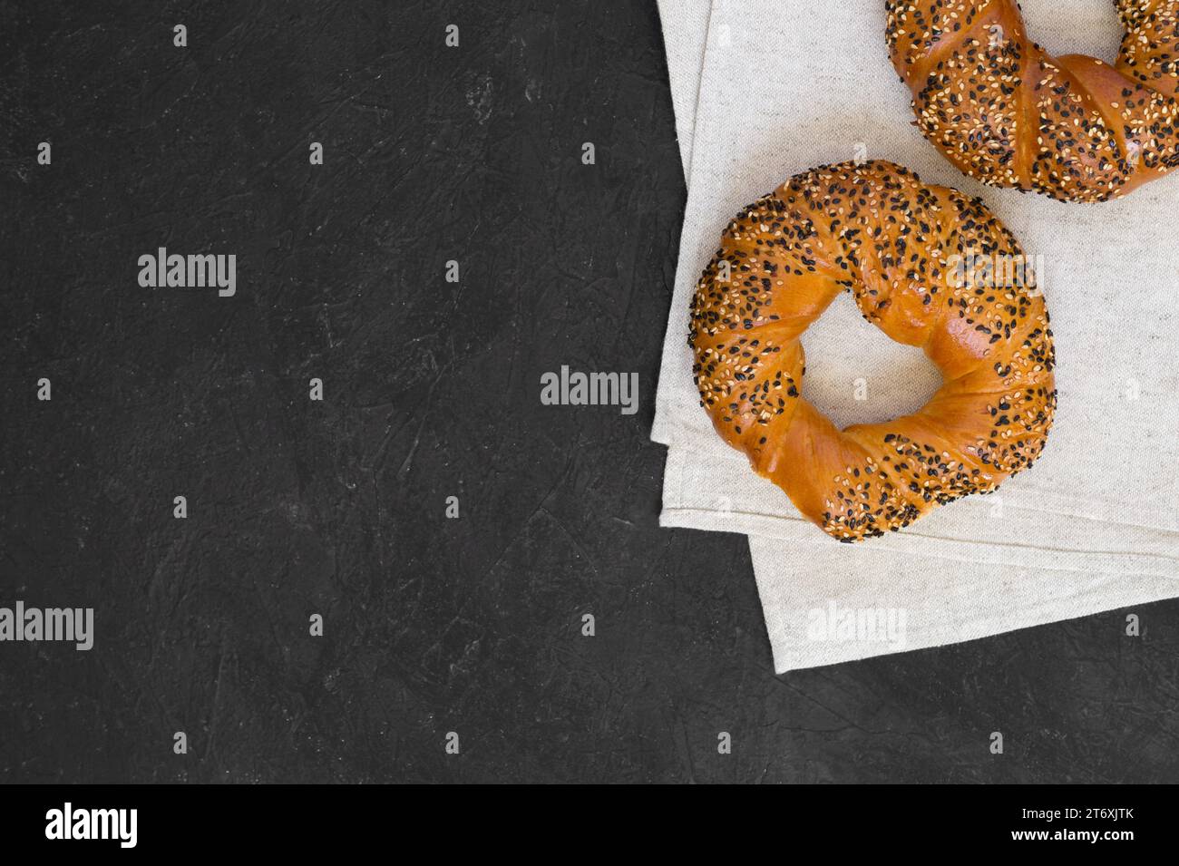 Tasty crispy bagel with white and black sesames on linen napkin, dark ...
