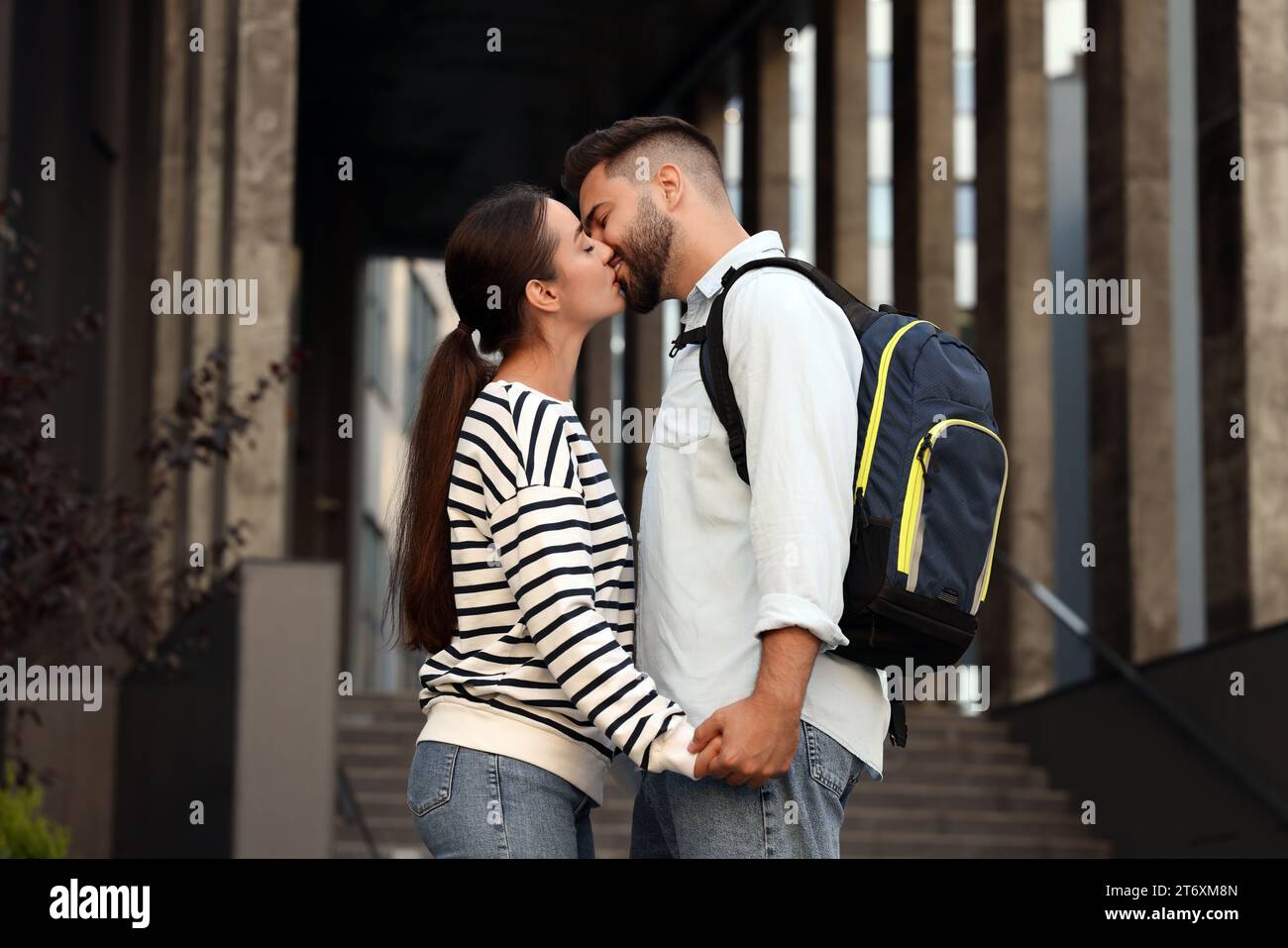 Long-distance relationship. Man with backpack kissing his girlfriend ...