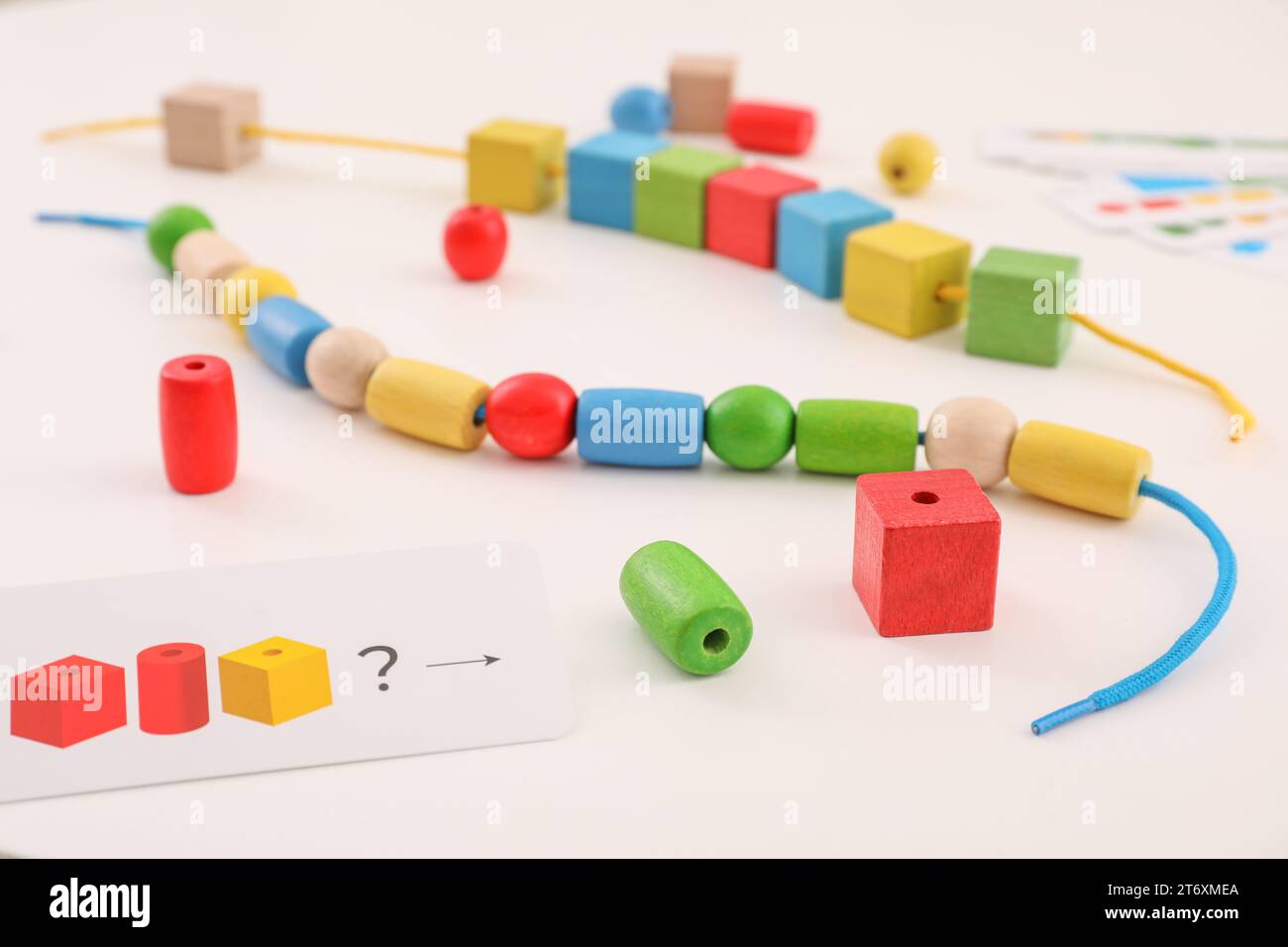 Wooden pieces and string for threading activity on white table. Motor ...