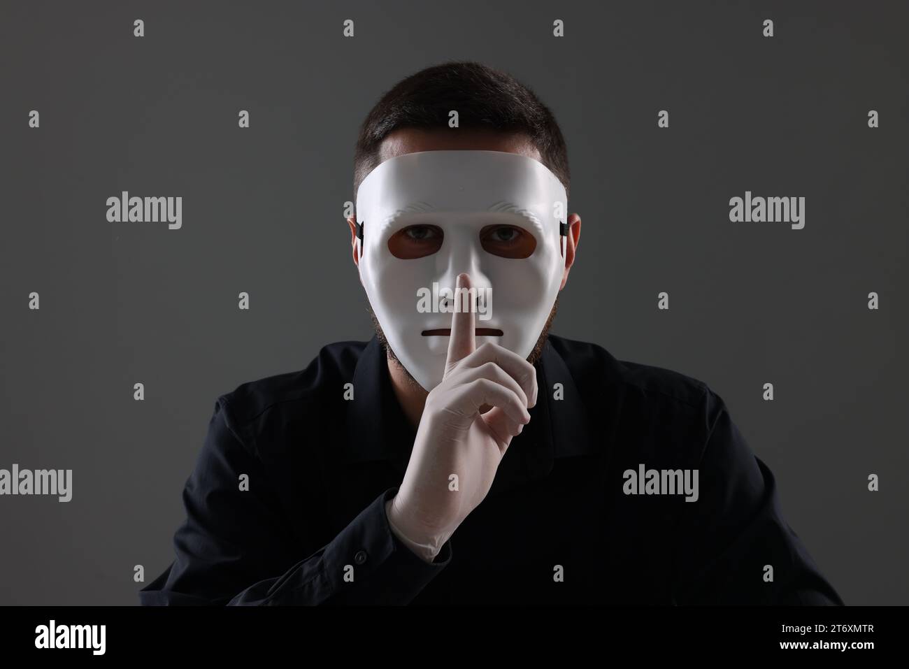 Man in mask and gloves showing hush gesture against grey background ...
