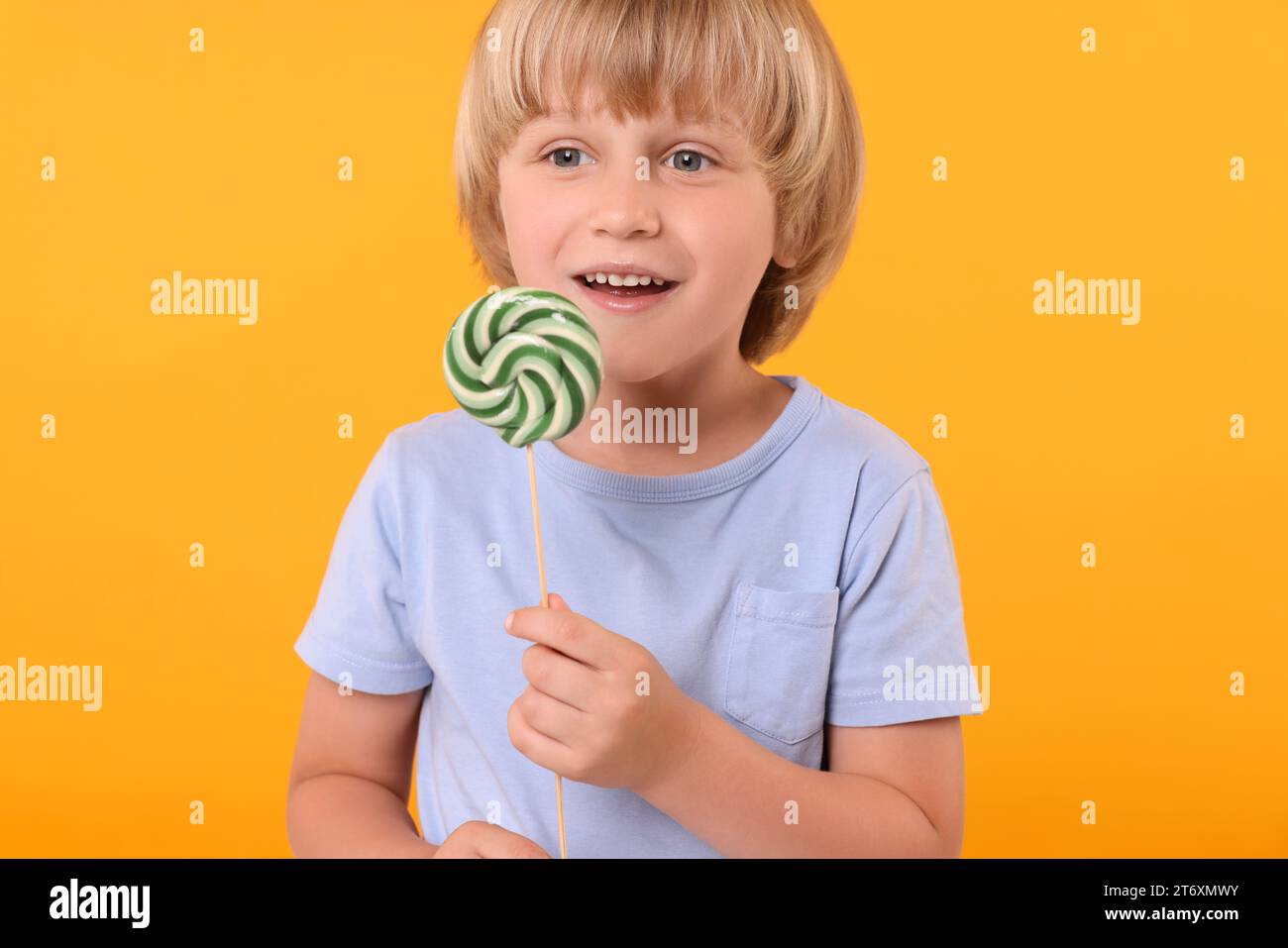 Happy little boy with lollipop swirl on orange background Stock Photo ...
