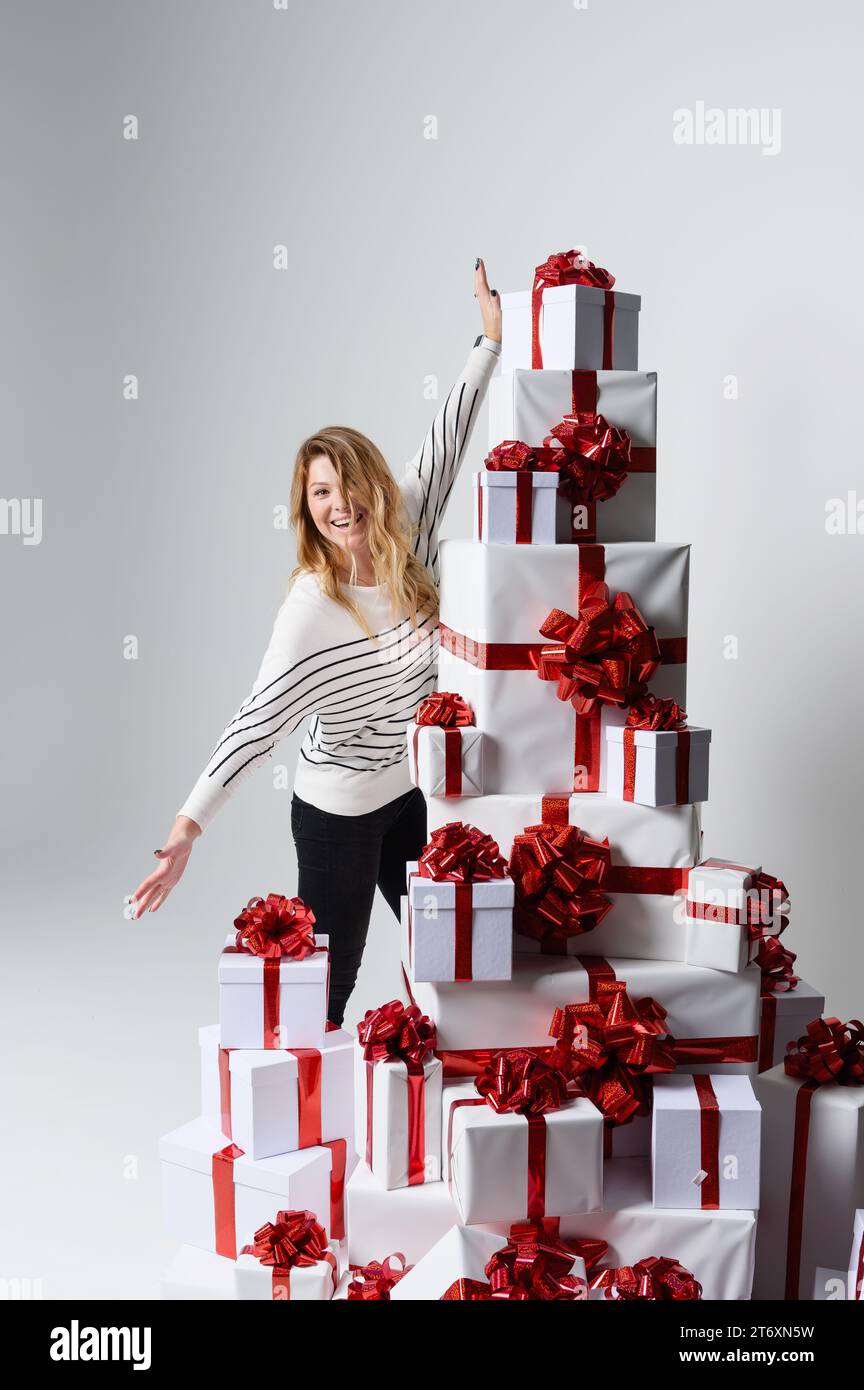 A gorgeous beautiful young woman poses among a mountain of white gift ...
