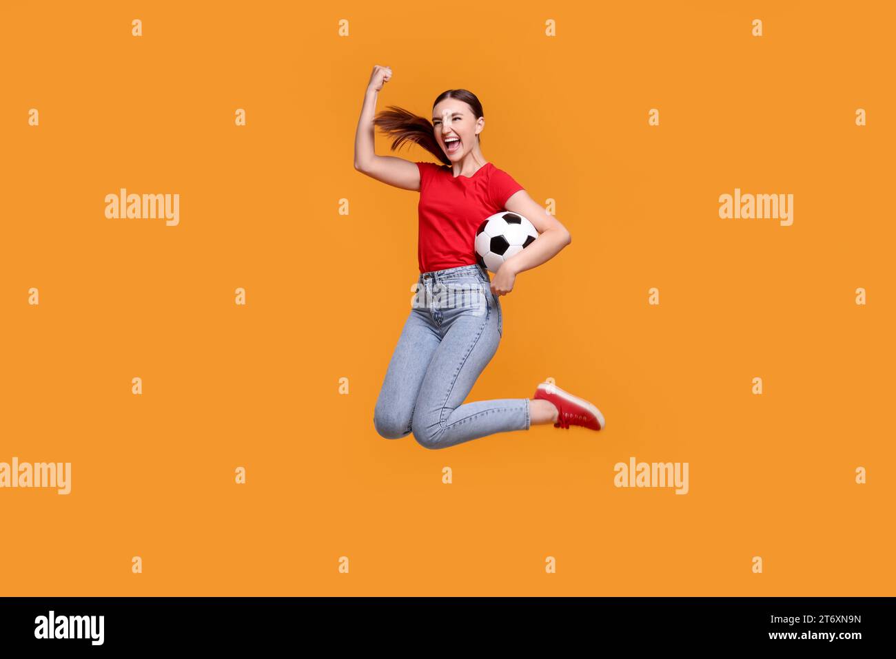 Emotional soccer fan with ball jumping on orange background Stock Photo ...