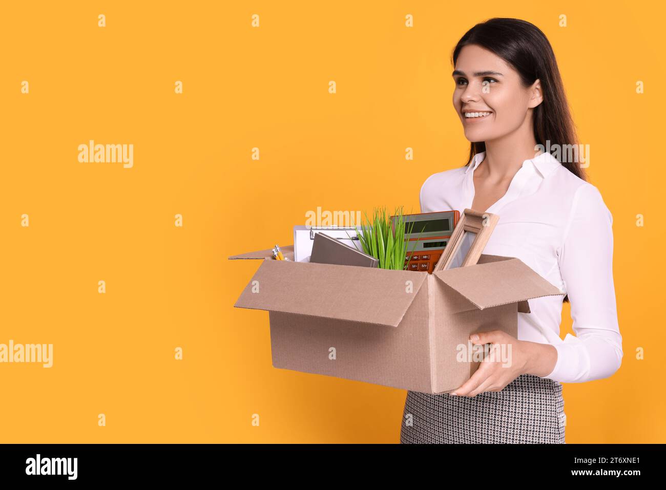 Happy unemployed woman with box of personal office belongings on orange ...