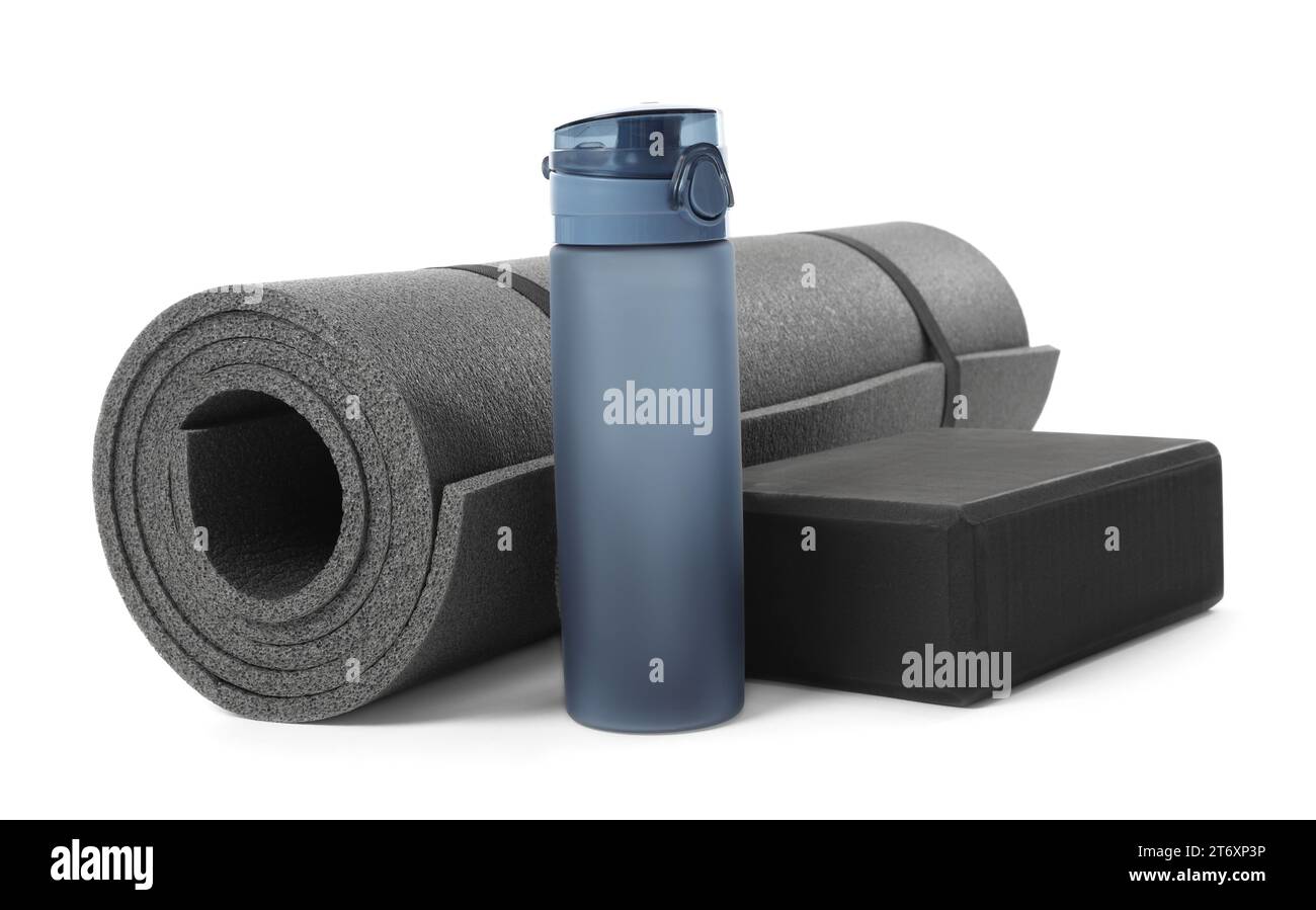 Grey exercise mat, yoga block and bottle of water isolated on white ...