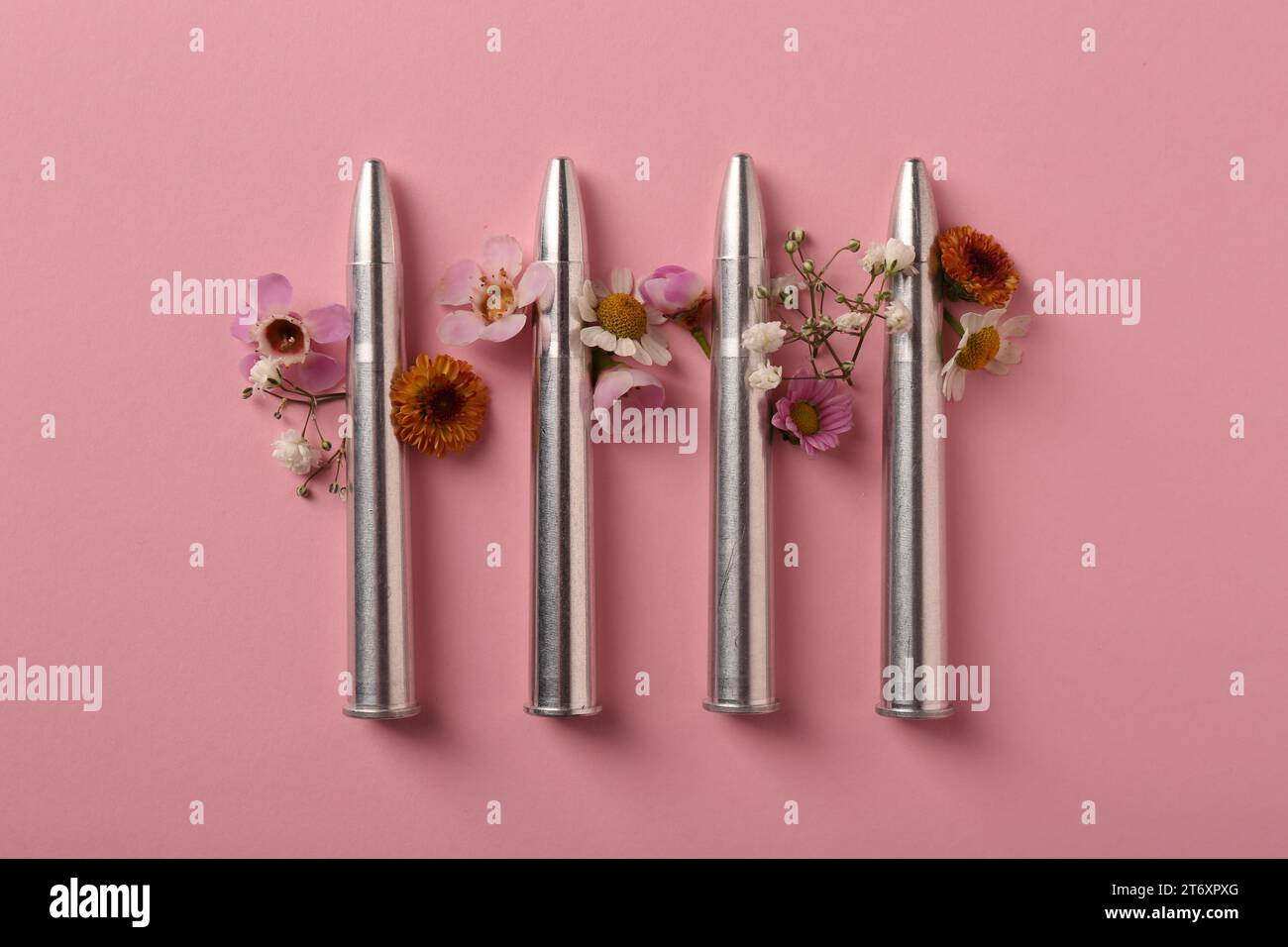 Metal bullets and beautiful flowers on pink background, flat lay Stock ...