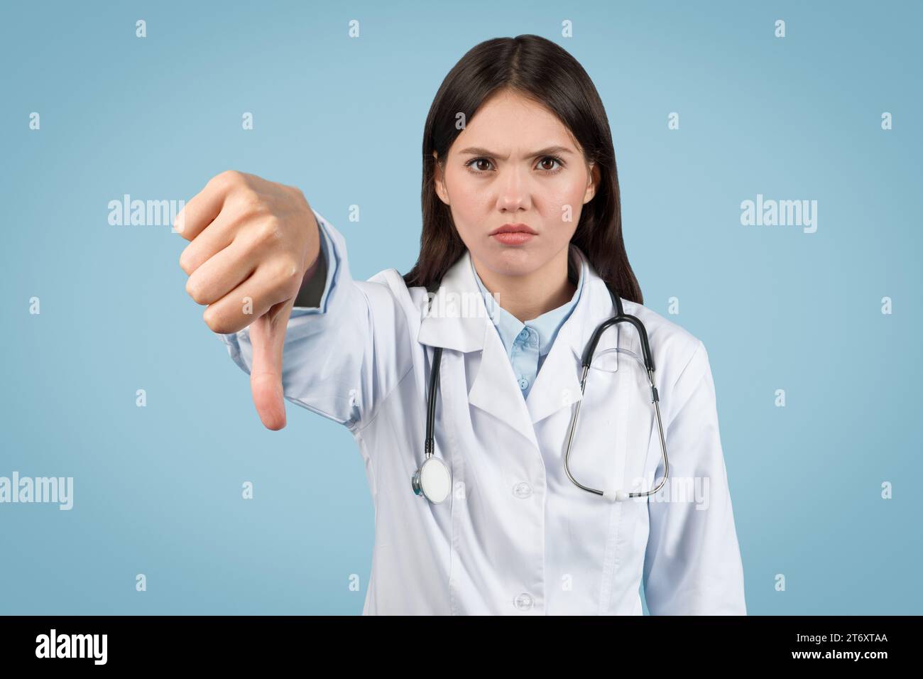 Stern female doctor giving thumbs down gesture Stock Photo - Alamy
