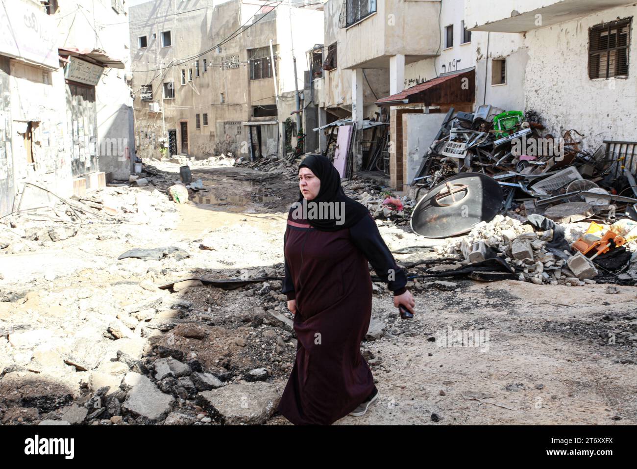 A woman walks through rubble of a destroyed building after an Israeli ...