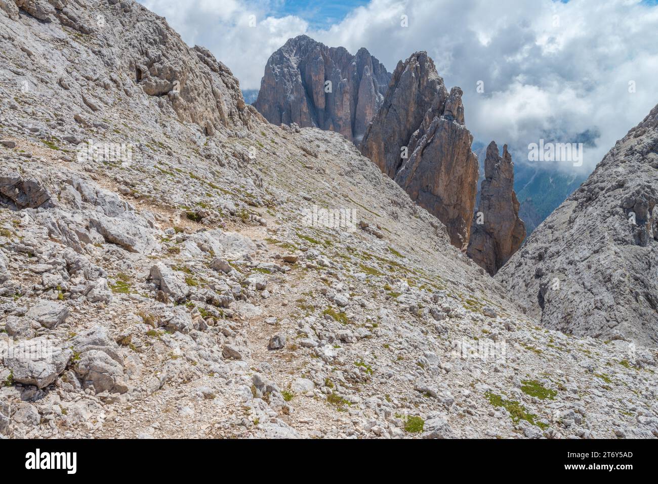Mountain trail leading down a rocky slope with huge limestone towers in ...