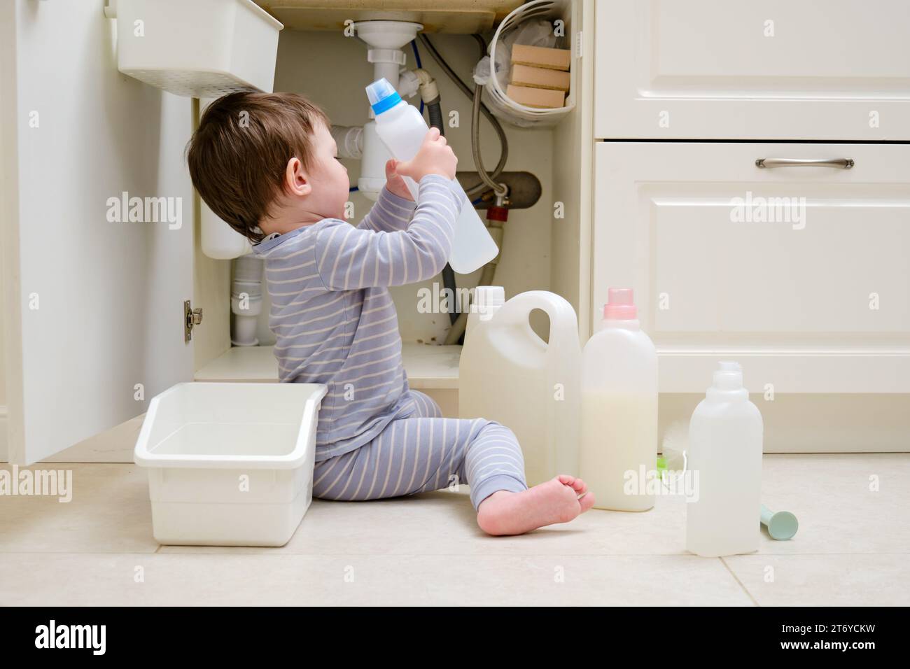 A child is playing with chemical cleaning products under the sink in ...
