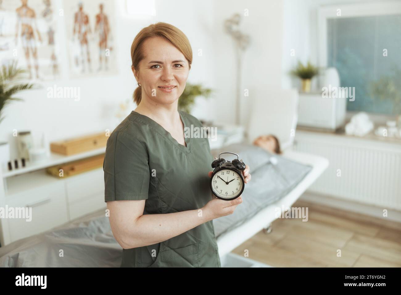 Healthcare time. happy female medical massage therapist in massage cabinet with client doing ...