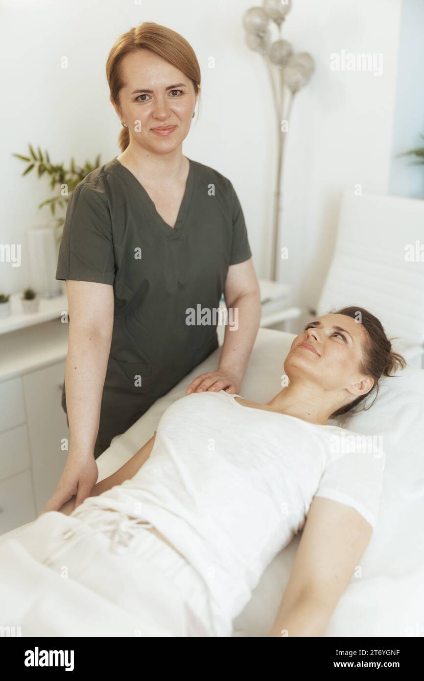 Healthcare time. happy female massage therapist in massage cabinet with client conducting ...