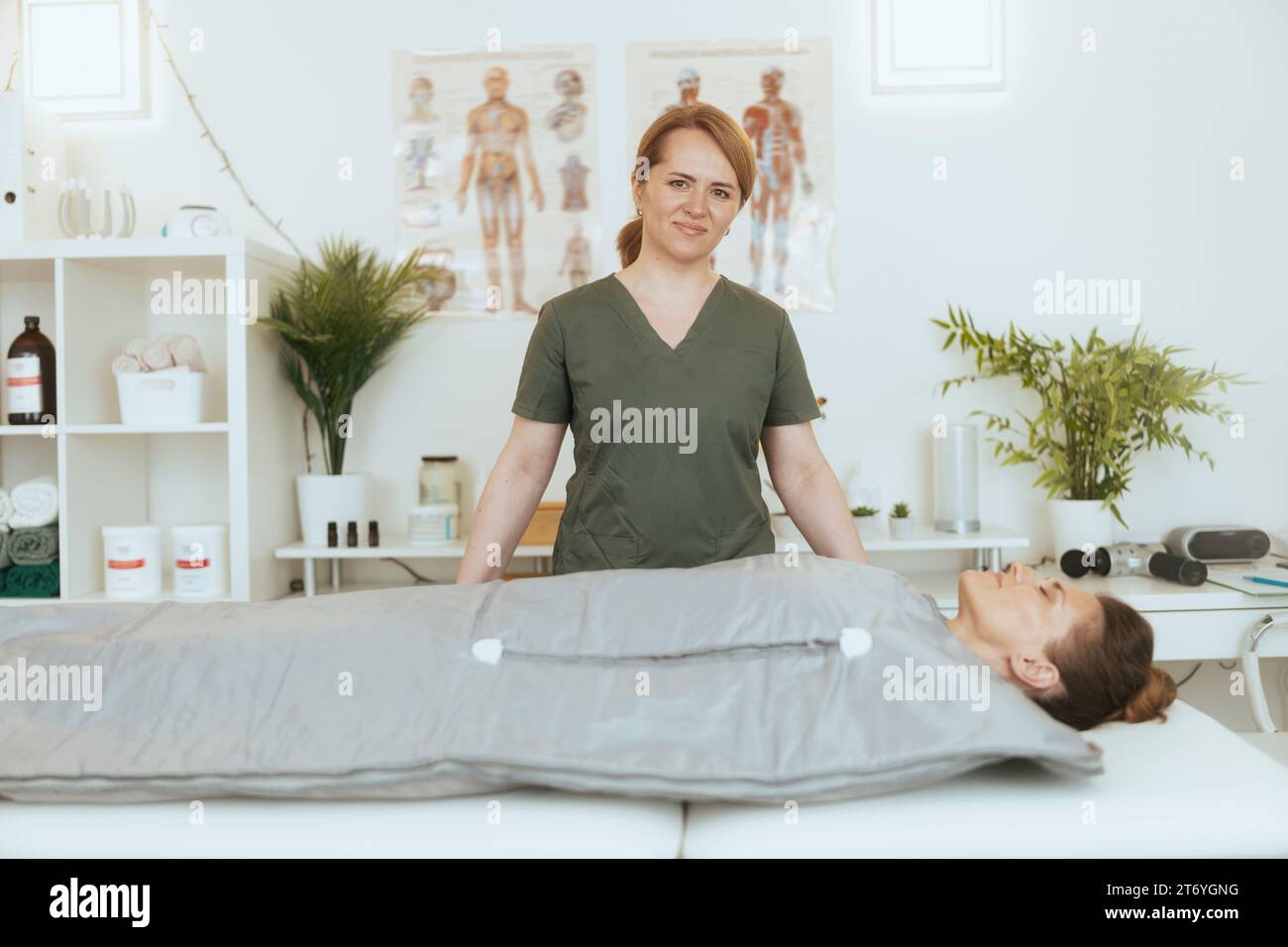 Healthcare time. smiling female massage therapist in massage cabinet with client doing whiskey ...
