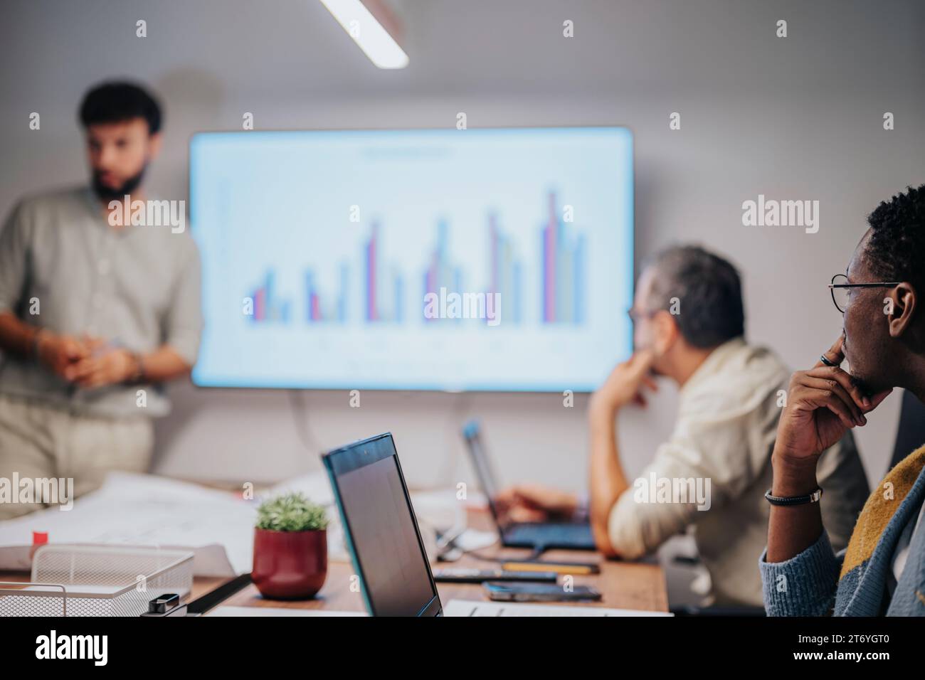 Diverse professionals discuss architectural blueprints and graph charts ...