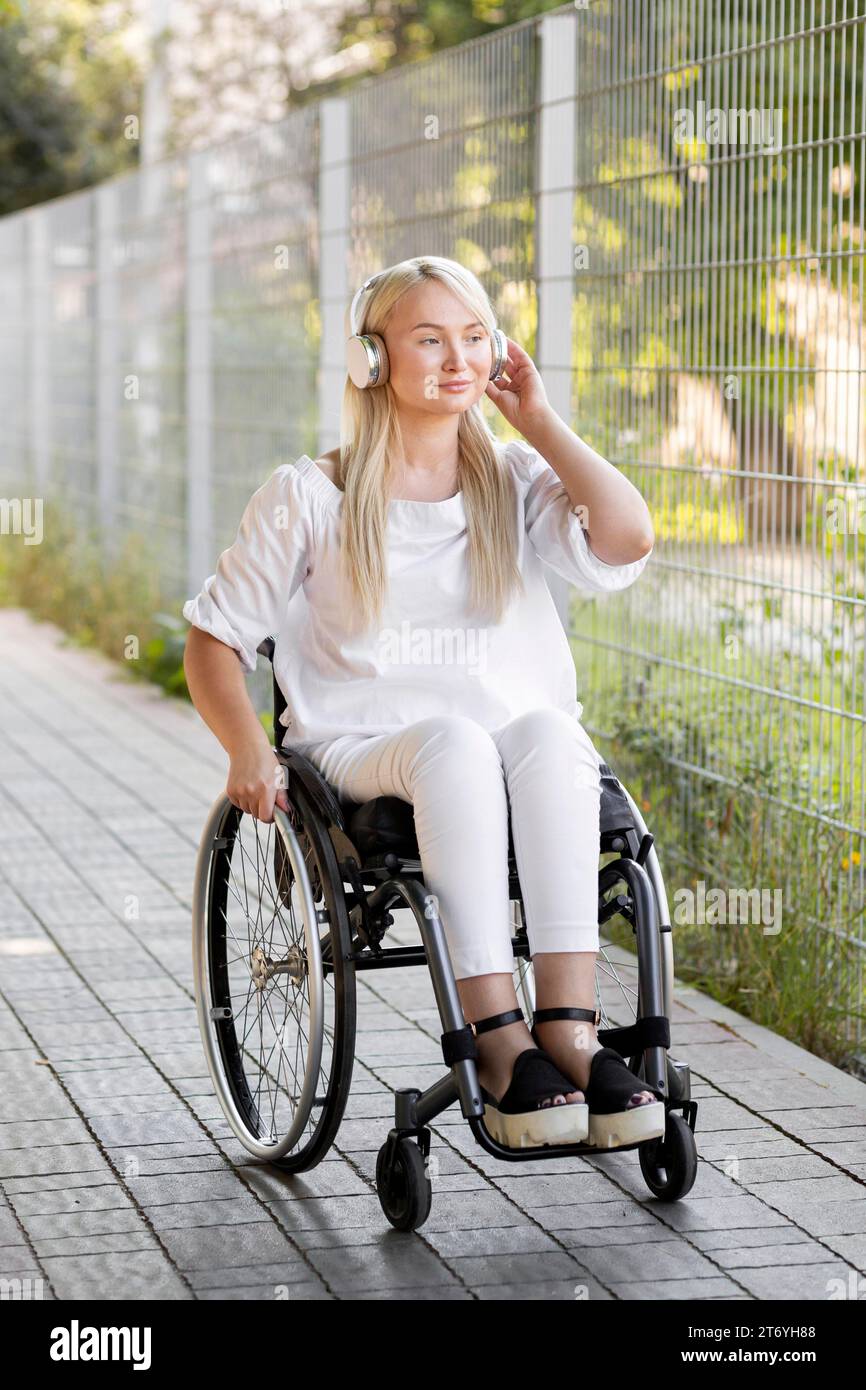 Smiley woman wheelchair with headphones outdoors Stock Photo - Alamy