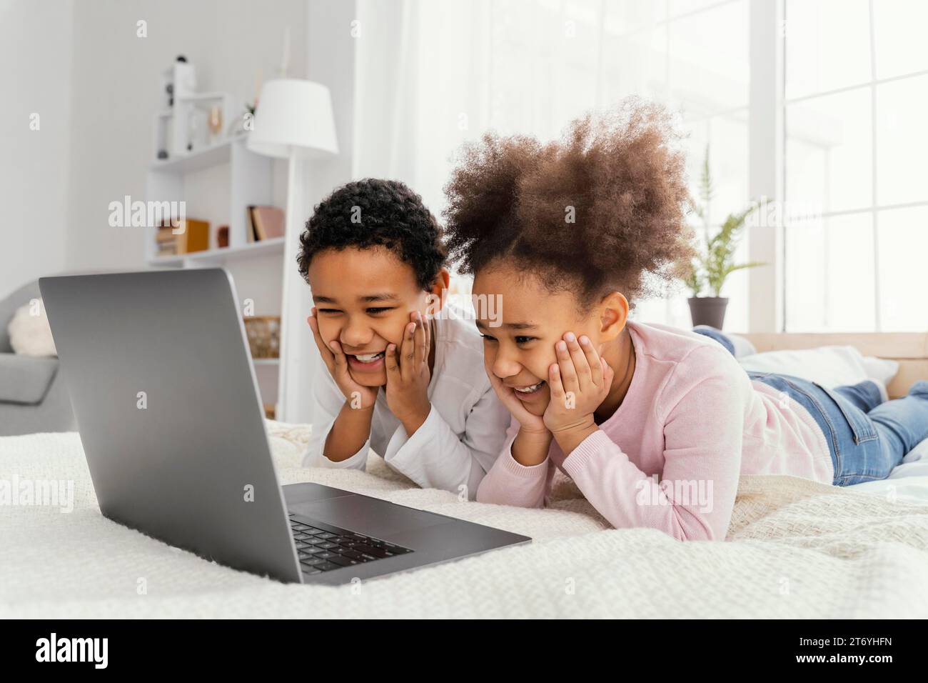 Two siblings home together playing laptop Stock Photo - Alamy