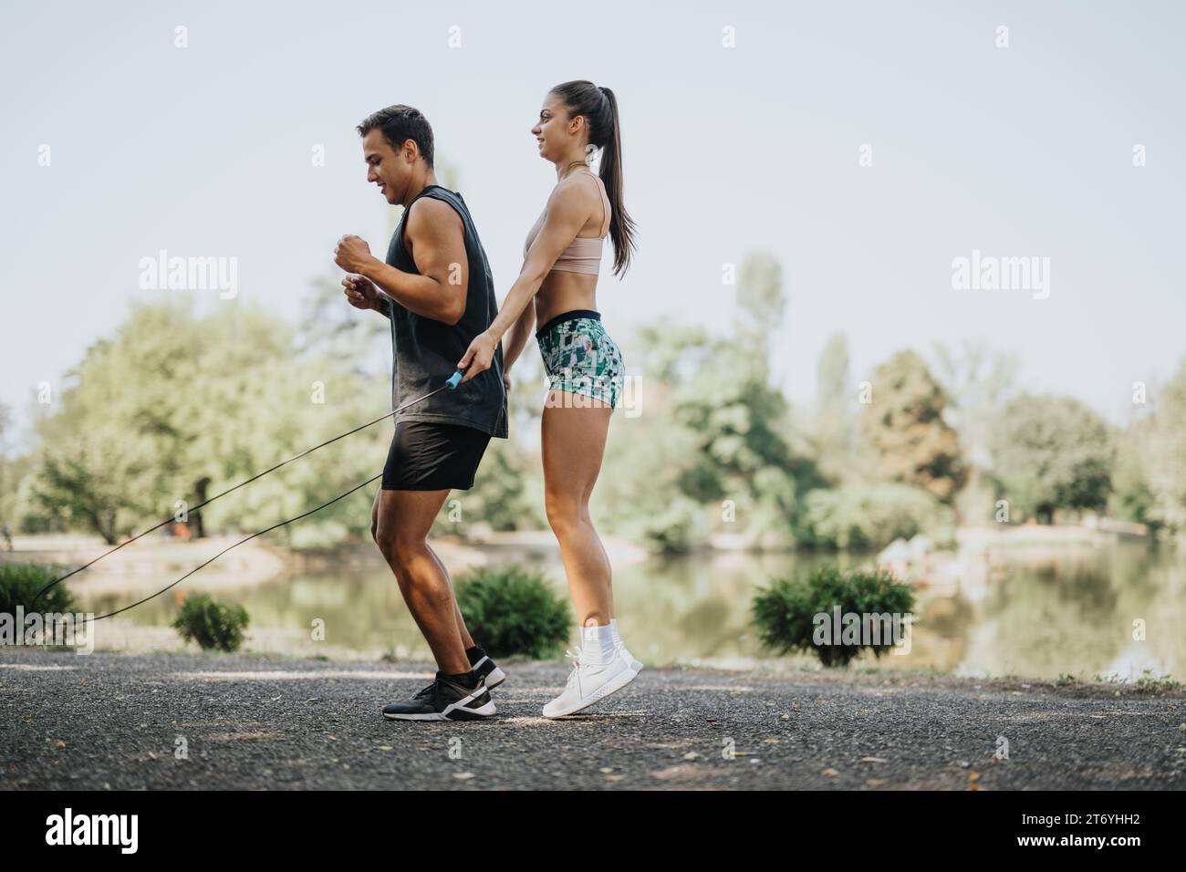 Fit couple jumps rope in sunny park, enjoying outdoors. Motivated and ...
