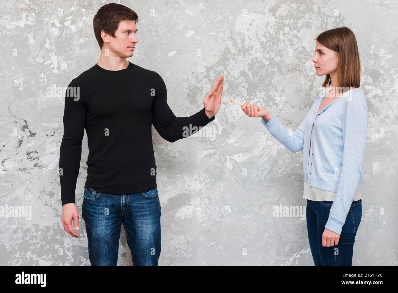 Young man saying no woman offering cigarette standing near old wall Stock Photo - Alamy